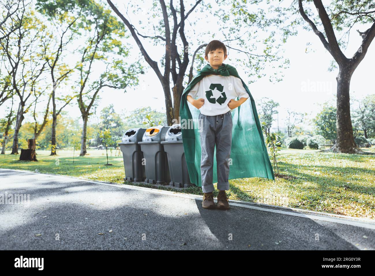 Cheerful young superhero boy with cape and recycle symbol promoting ...