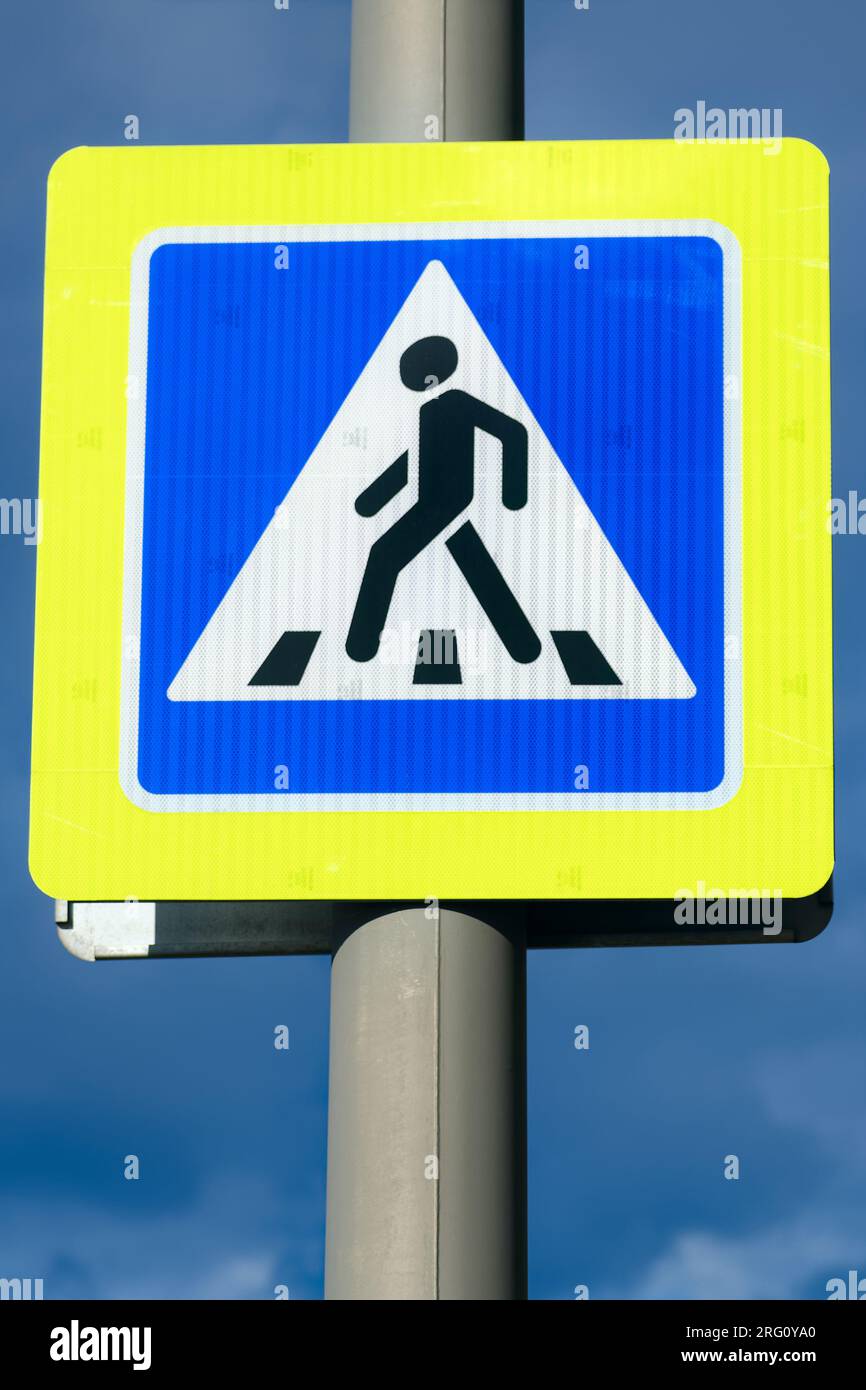 Close-up pedestrian crossing sign with bright yellow frame on cloudy ...