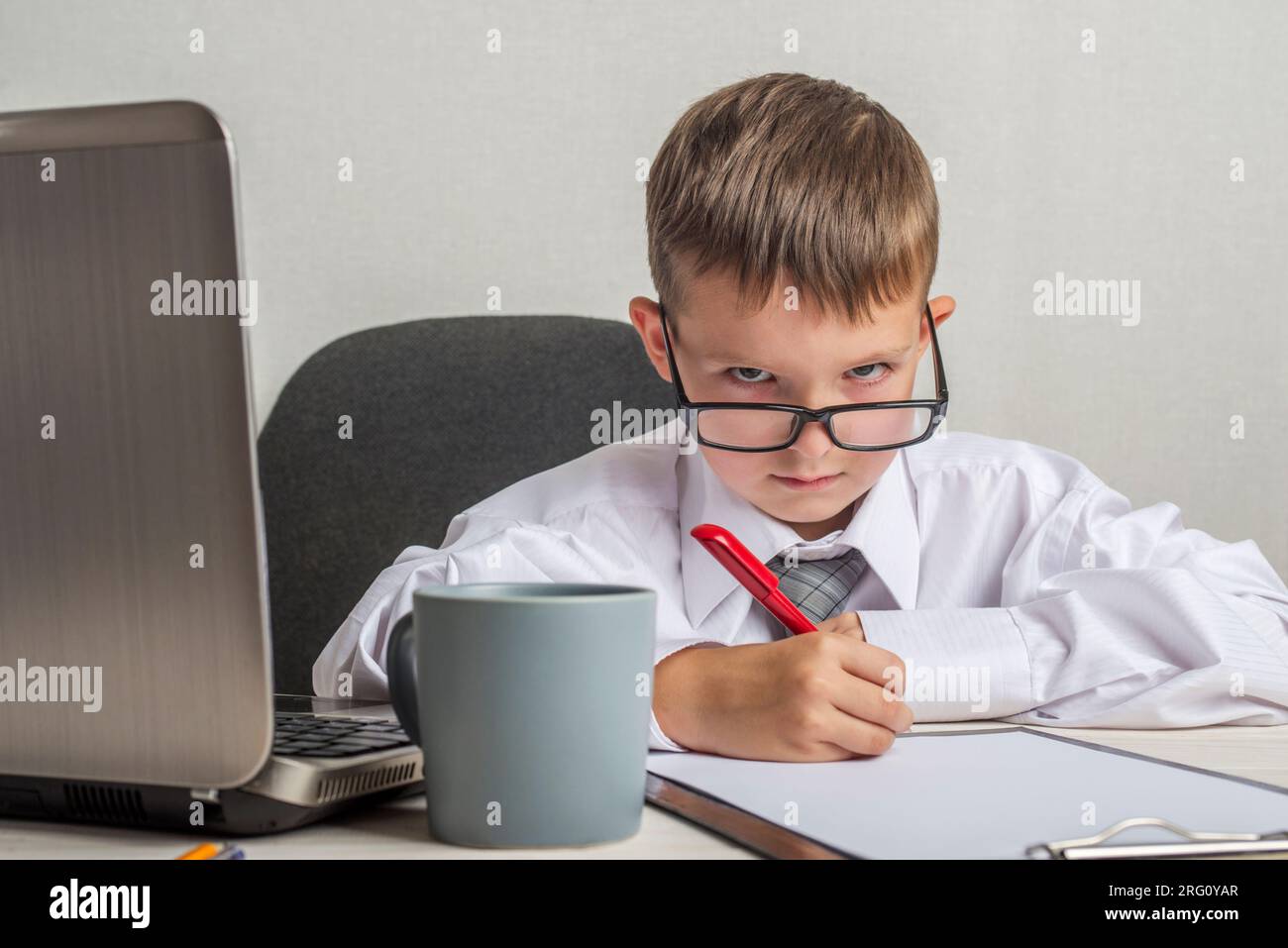 Serious child is writting on a clipboard in suit and glasses Stock ...