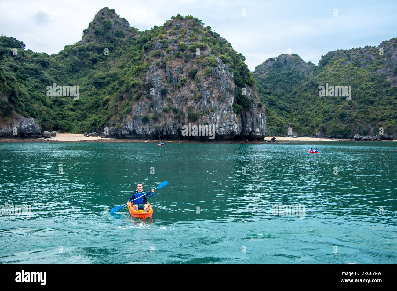 Kayaker on the water in front of a limestone karst island with ...