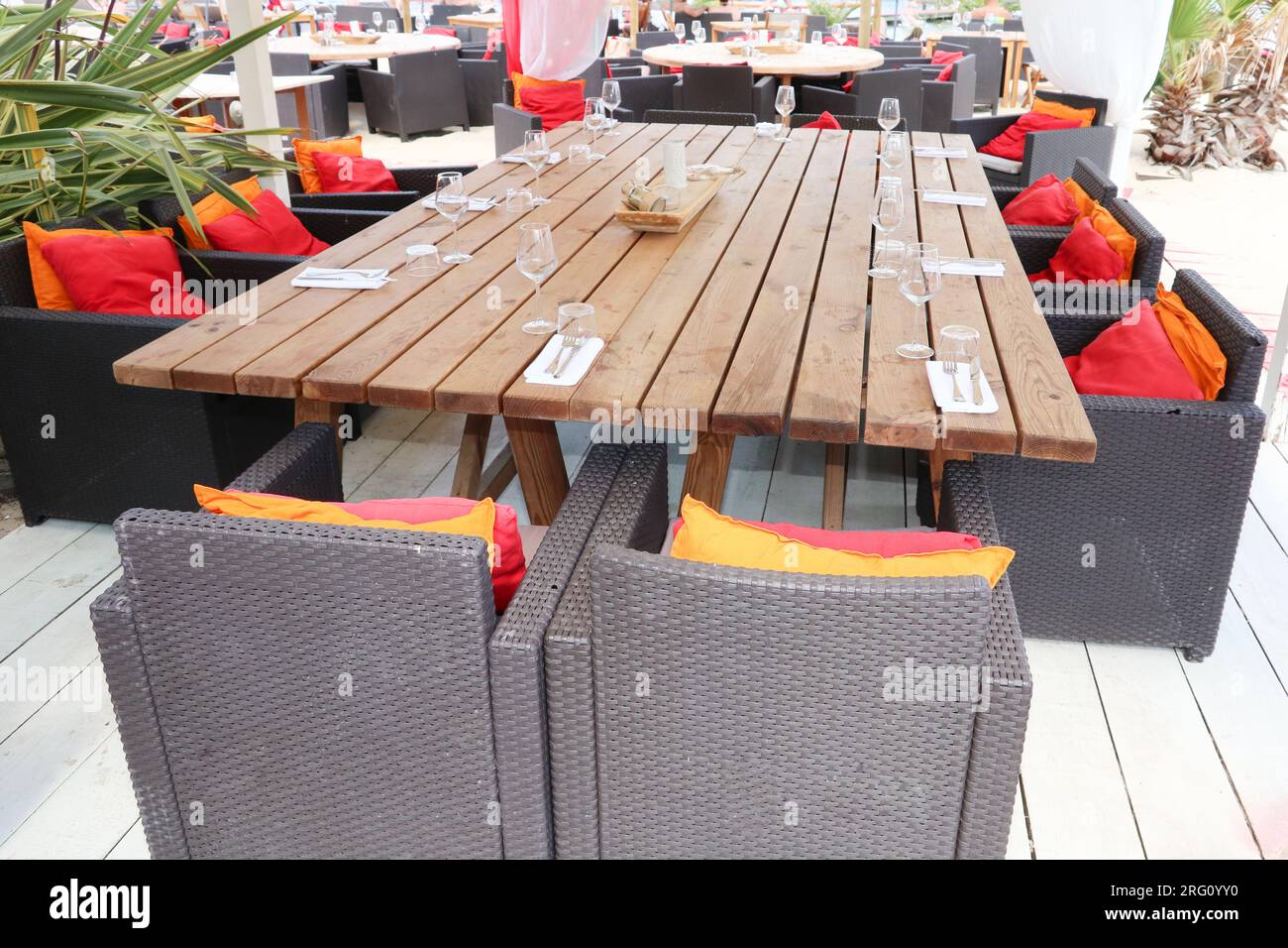 the terrace of a restaurant with a large wooden table for ten people ...
