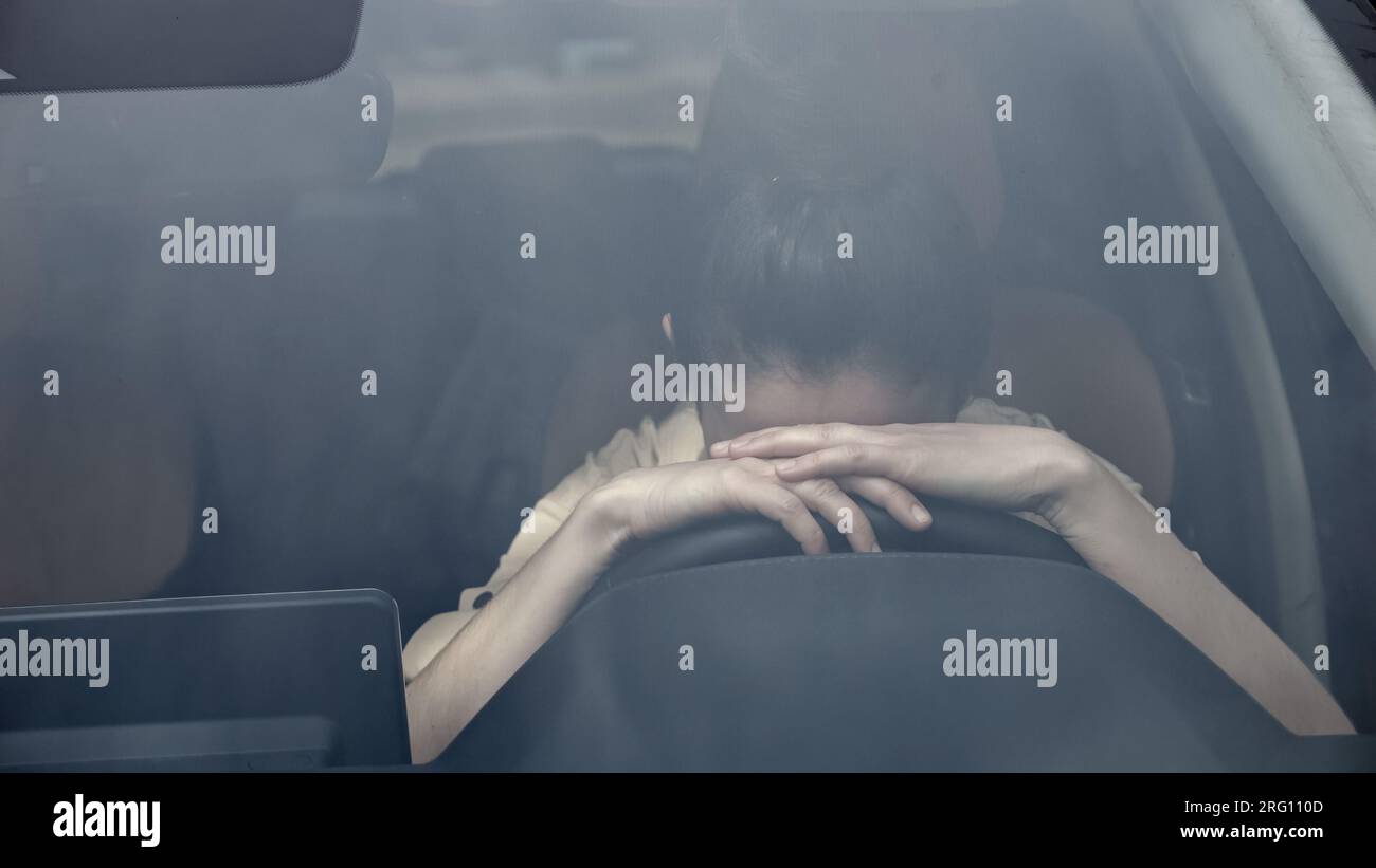 Woman sits in car with sad expression view through windshield Stock ...
