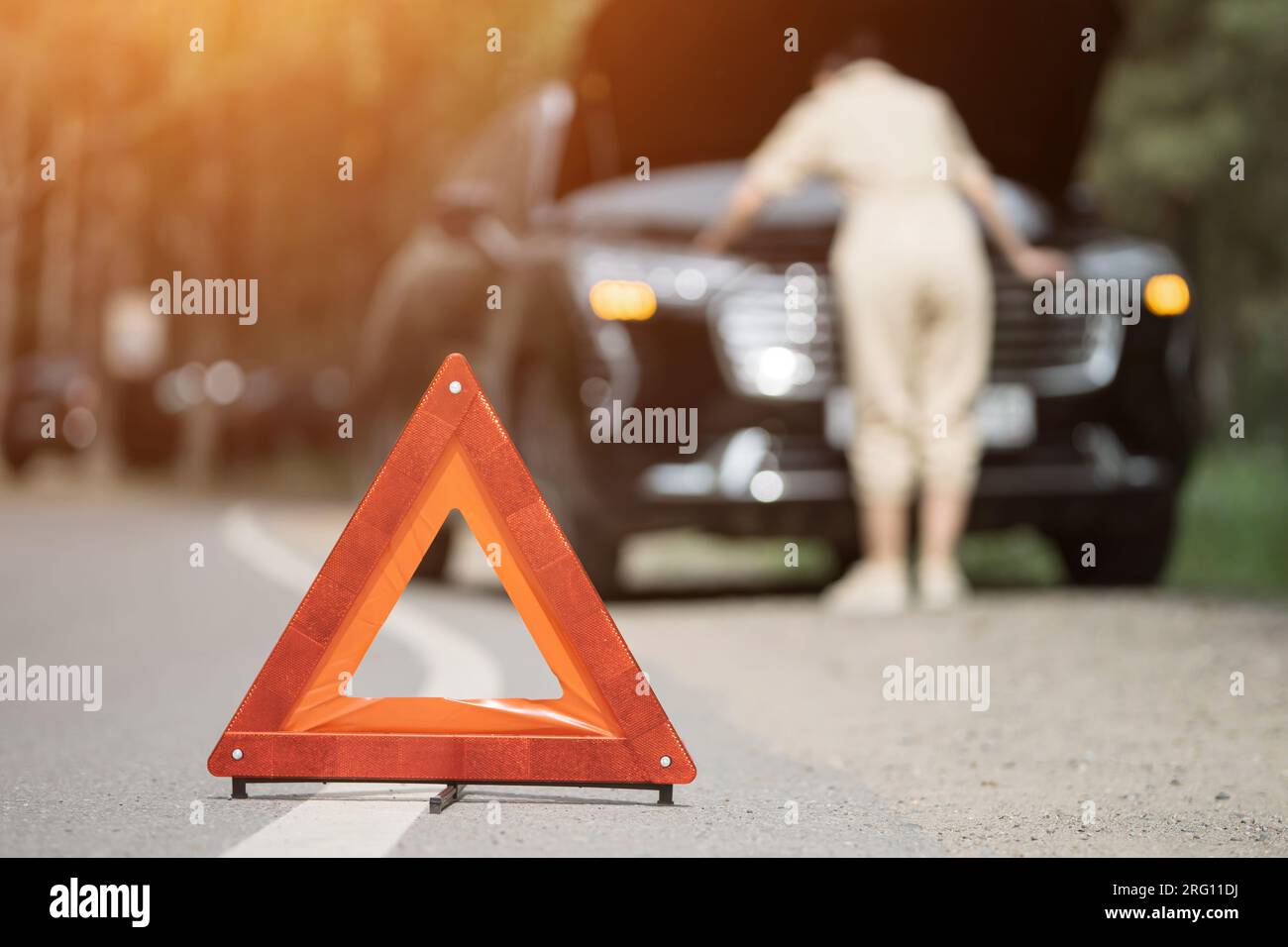 Warning triangle against woman driver trying to fix defect in engine ... Warning triangle against woman driver trying to fix defect in engine ...