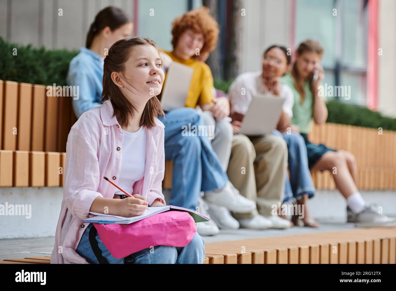 back to school, happy girl taking notes near teen classmates and ...
