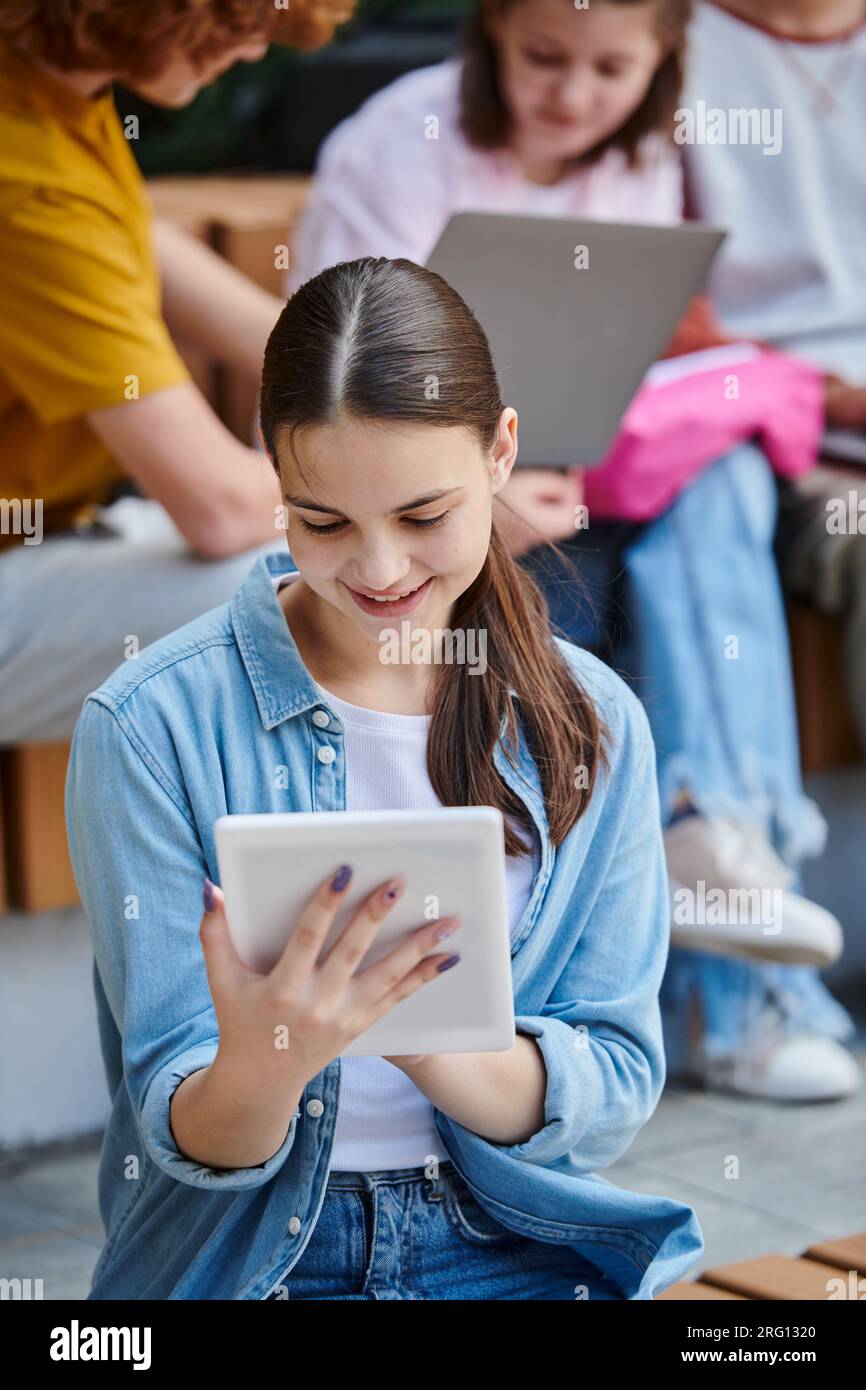 back to school, teen girl using gadget near blurred classmates outdoors ...