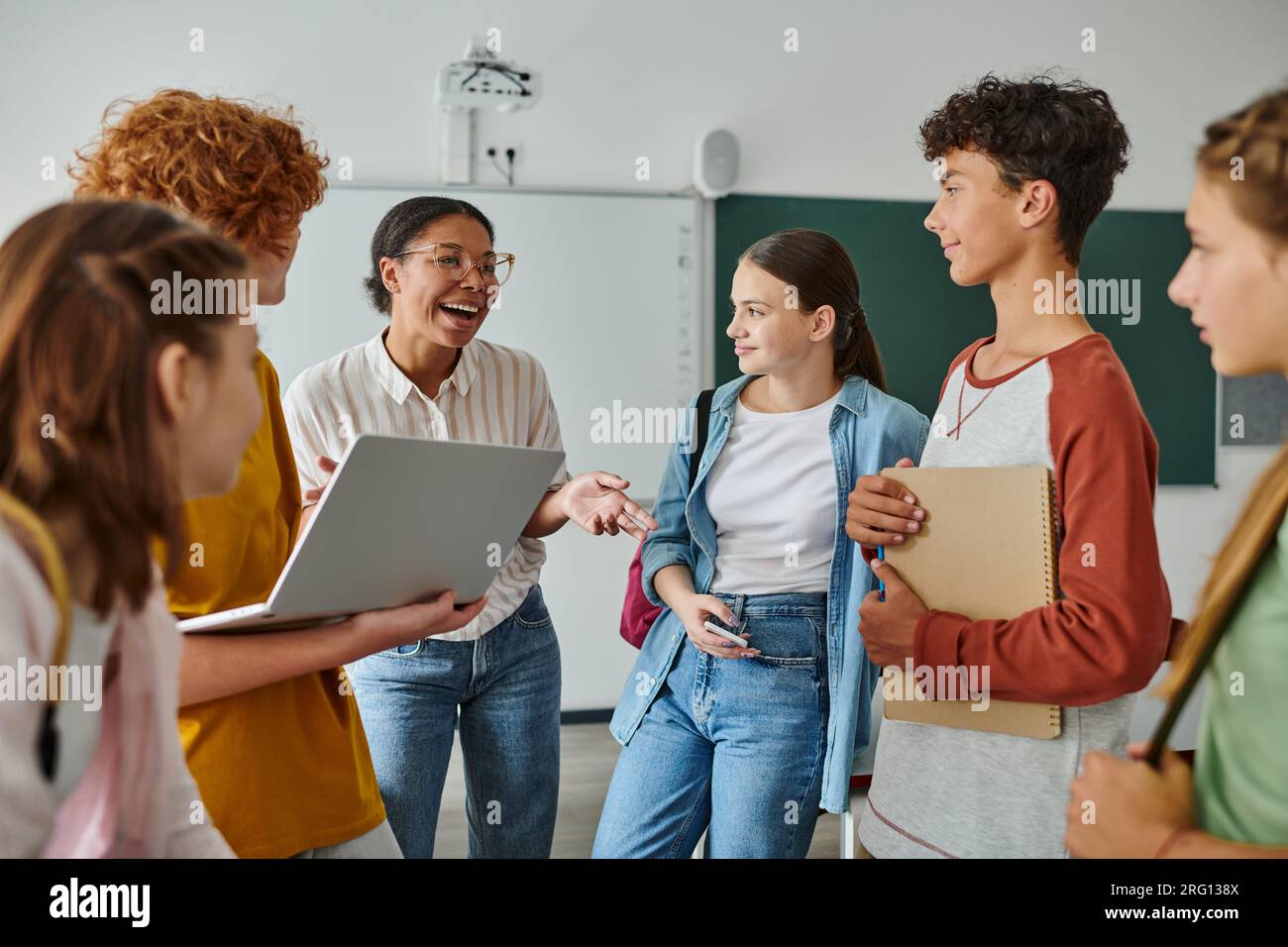 cheerful african american teacher laughing with teenage students in ...