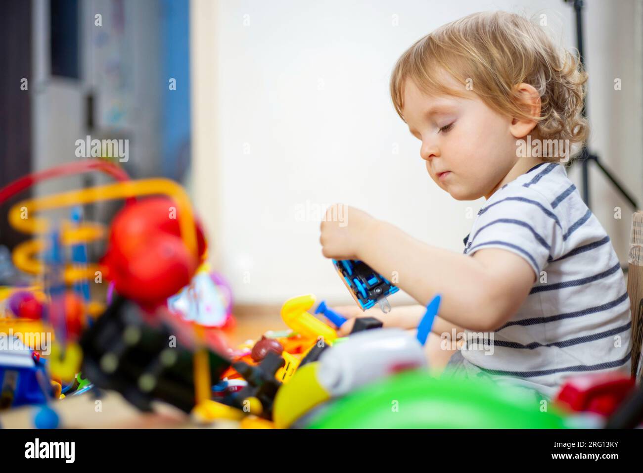 A huge bunch of different and colored toys in front of playful child ...