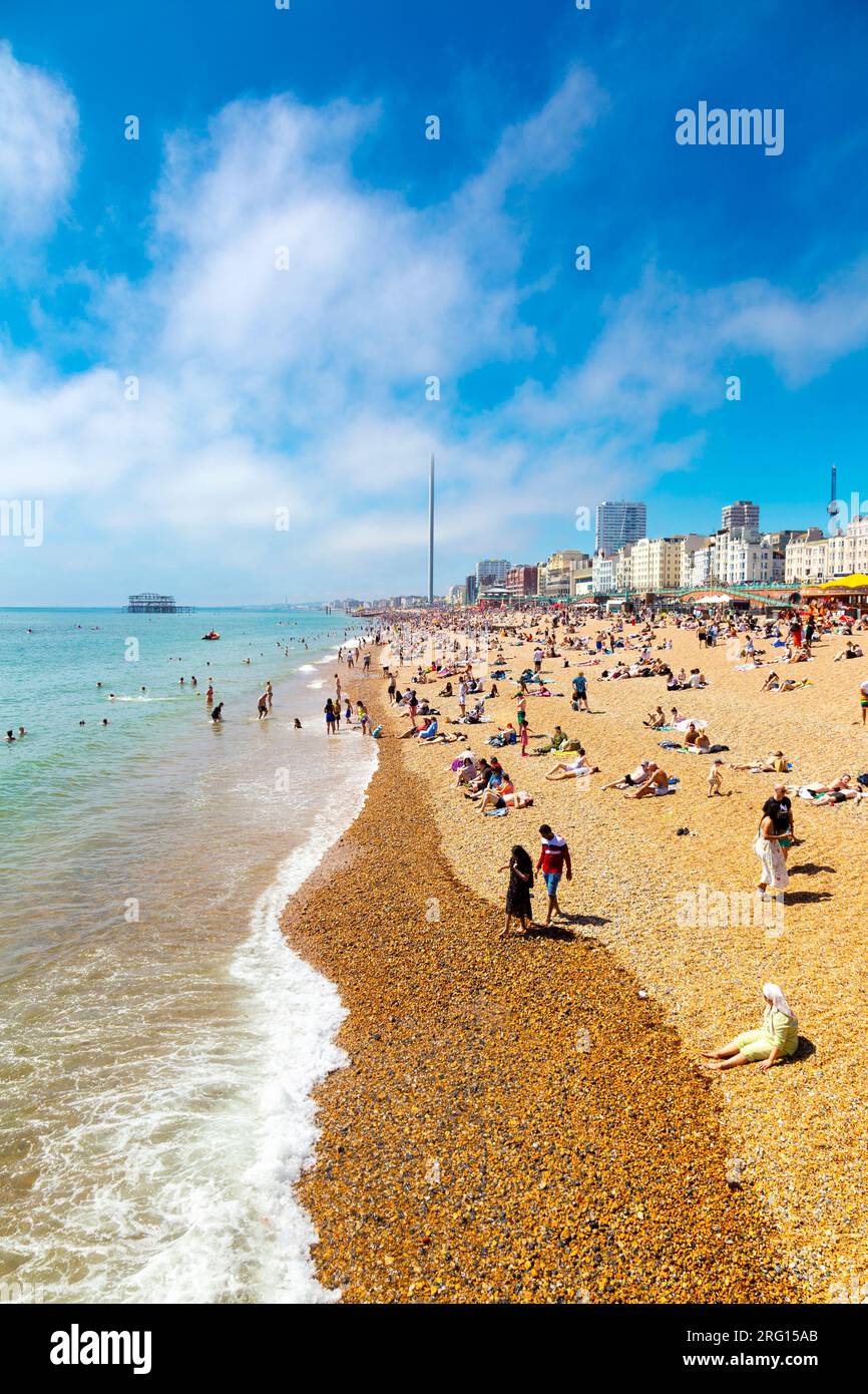 People sitting on the beach on a hot summer day with the burned down ...