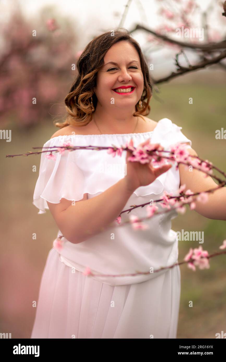 Woman peach blossom. Happy woman in white dress walking in the garden ...