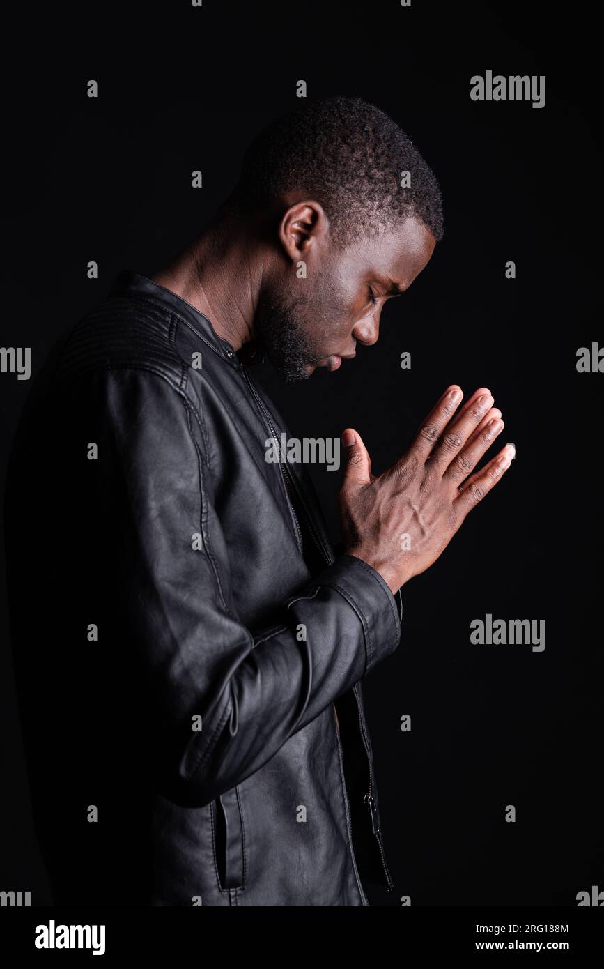 Side view of calm young African American male in jacket with eyes closed while standing with ...