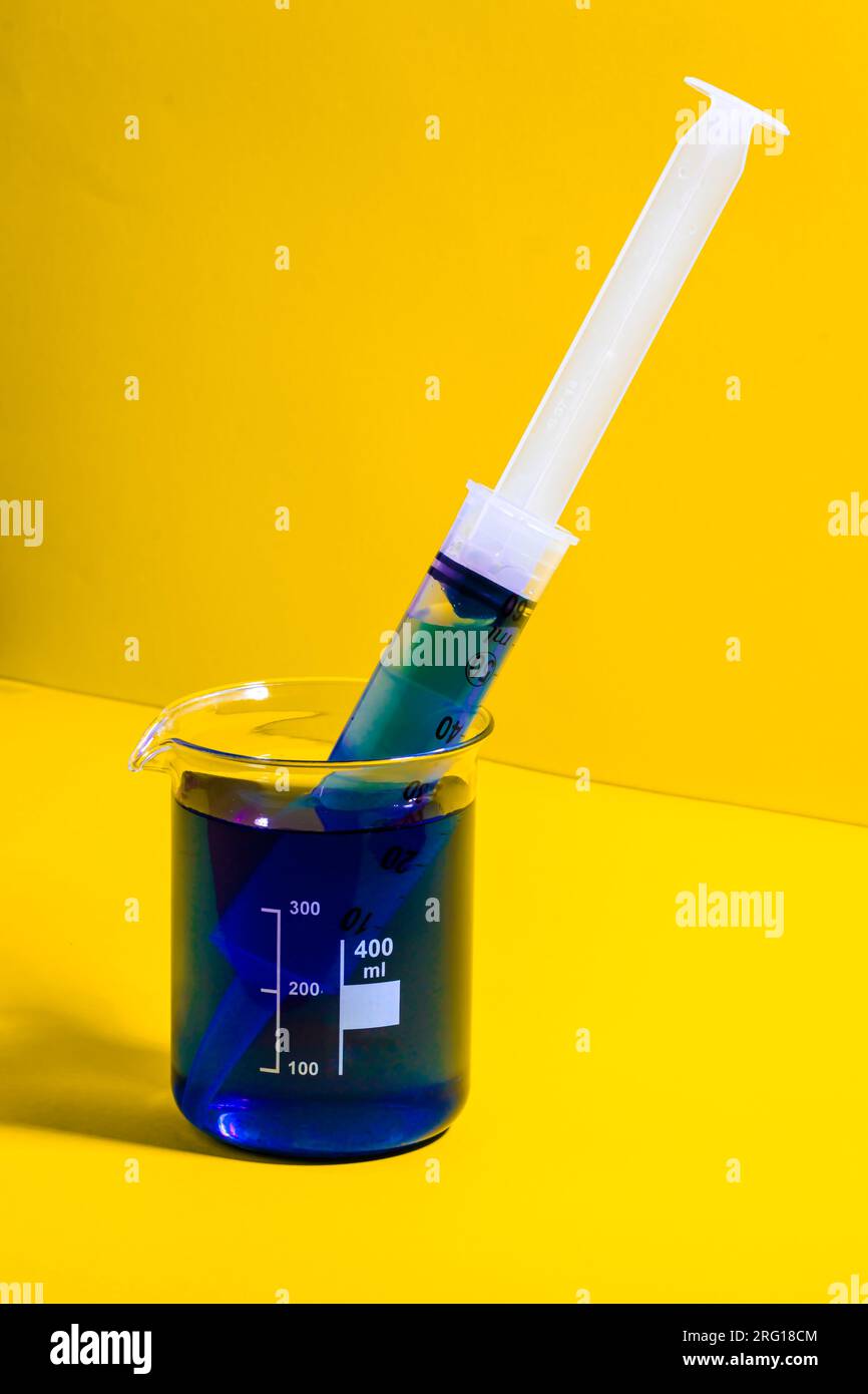 High angle of plastic syringe placed in transparent beaker filled wit ...