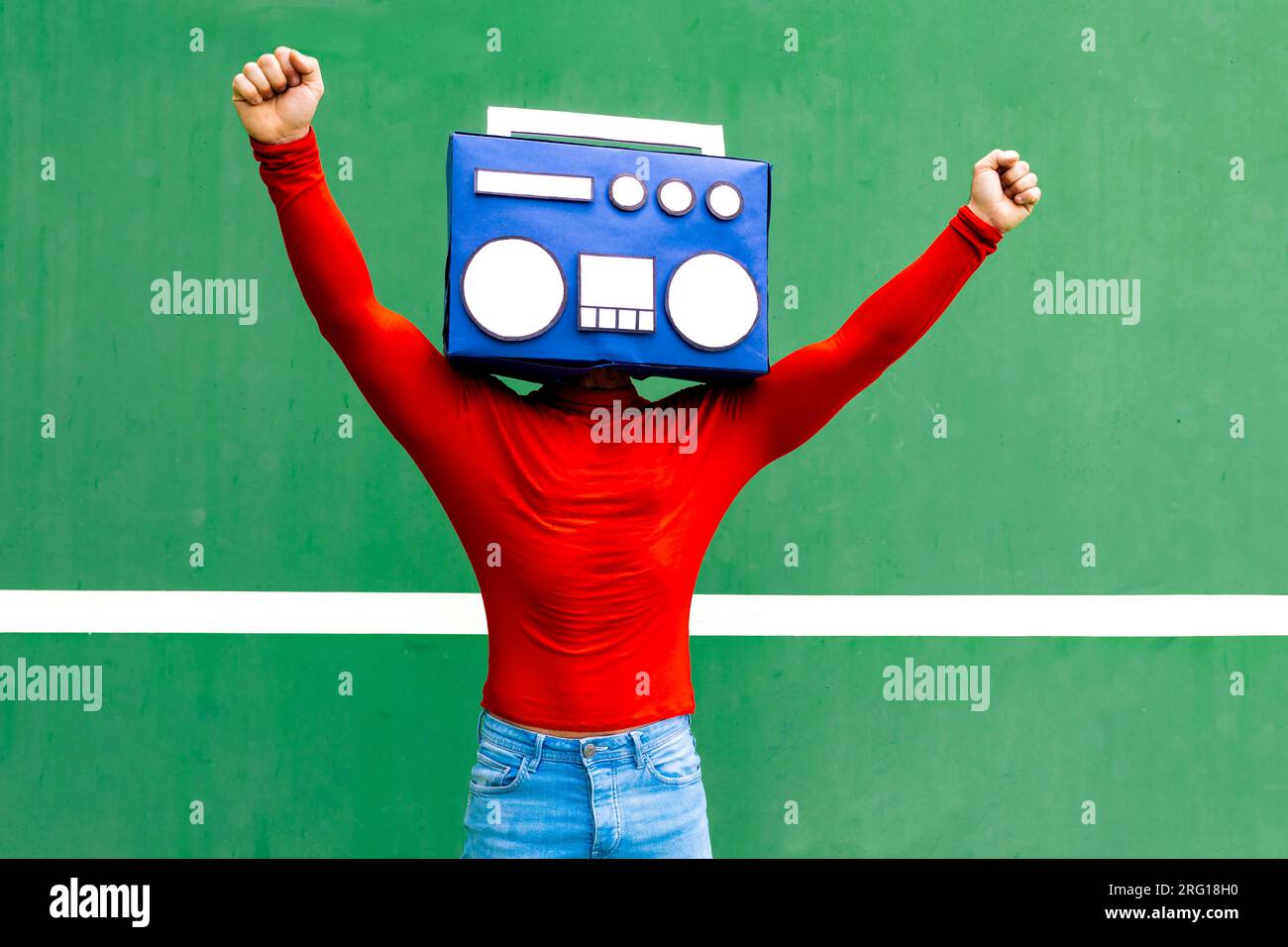 Anonymous male in casual outfit covering face with blue boombox raising ...