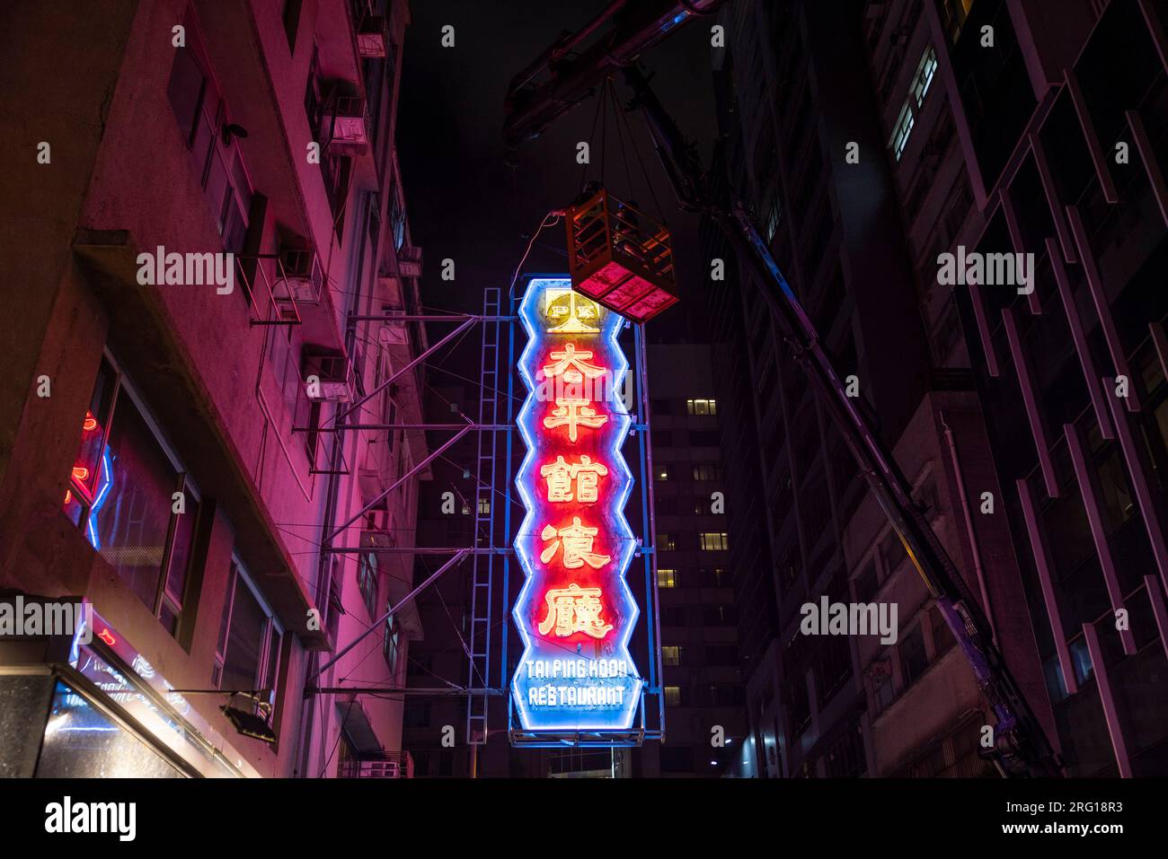 Workers remove a neon sign that was hung on Tai Ping Koon restaurant ...