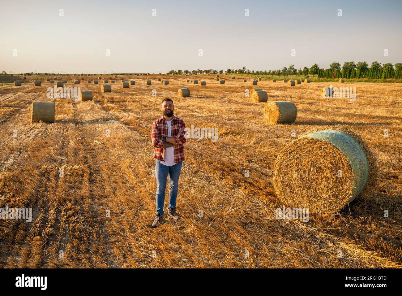 Happy farmer is standing beside bales of hay. He is satisfied because ...