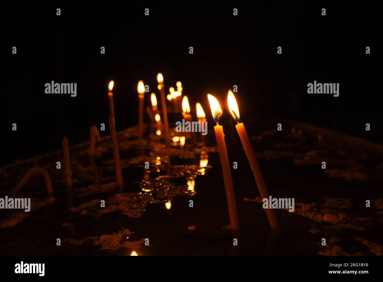 Close-up of two burning candles standing tilted towards each other ...