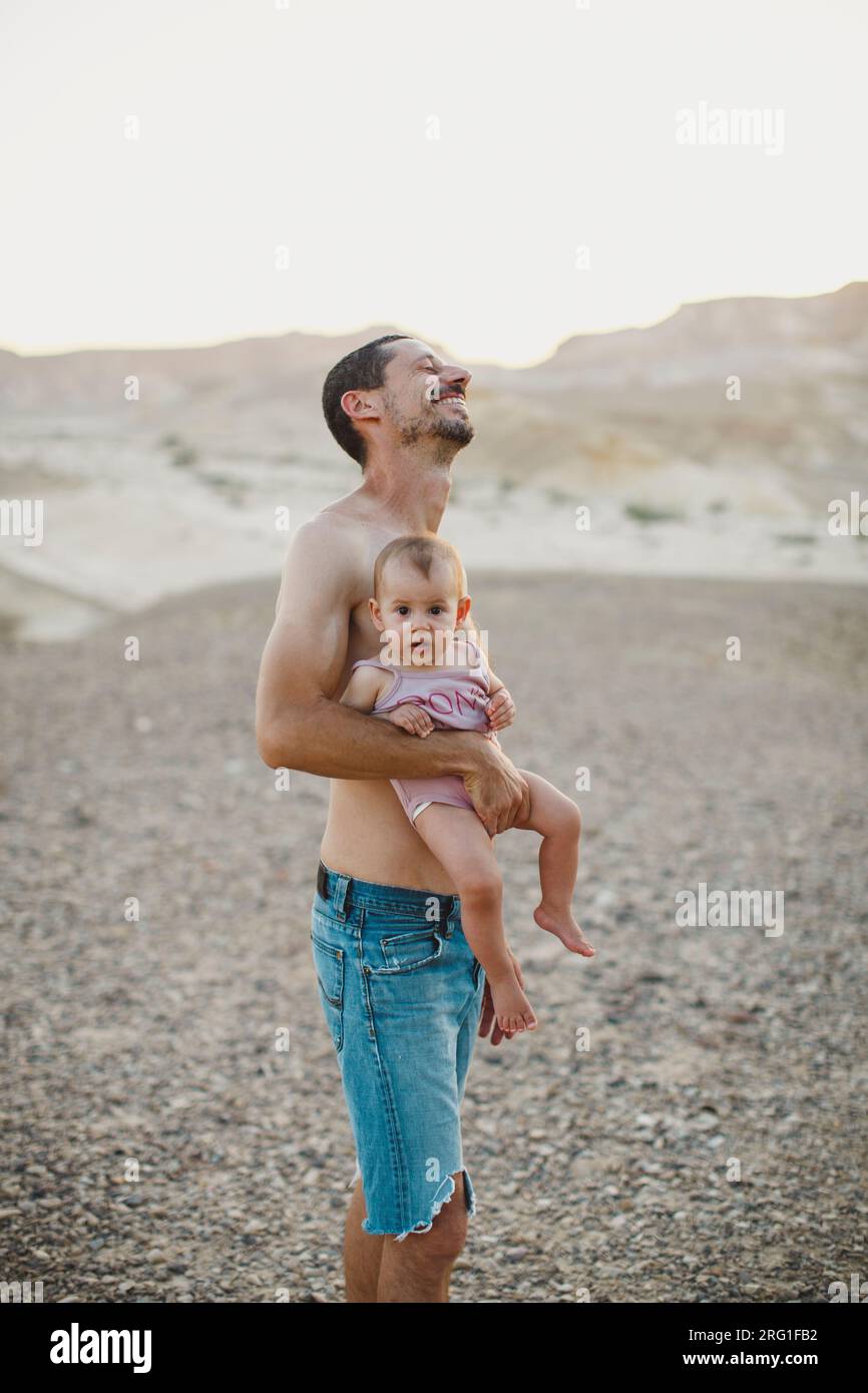 A father laughing while holding his baby girl in the desert Stock Photo ...
