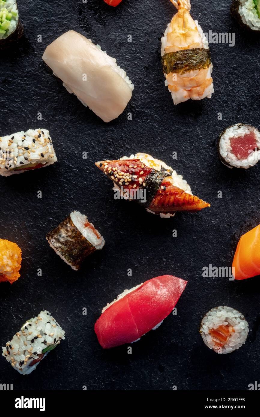 Sushi variety, shot from the top. Rolls, maki, nigiri on a black slate ...