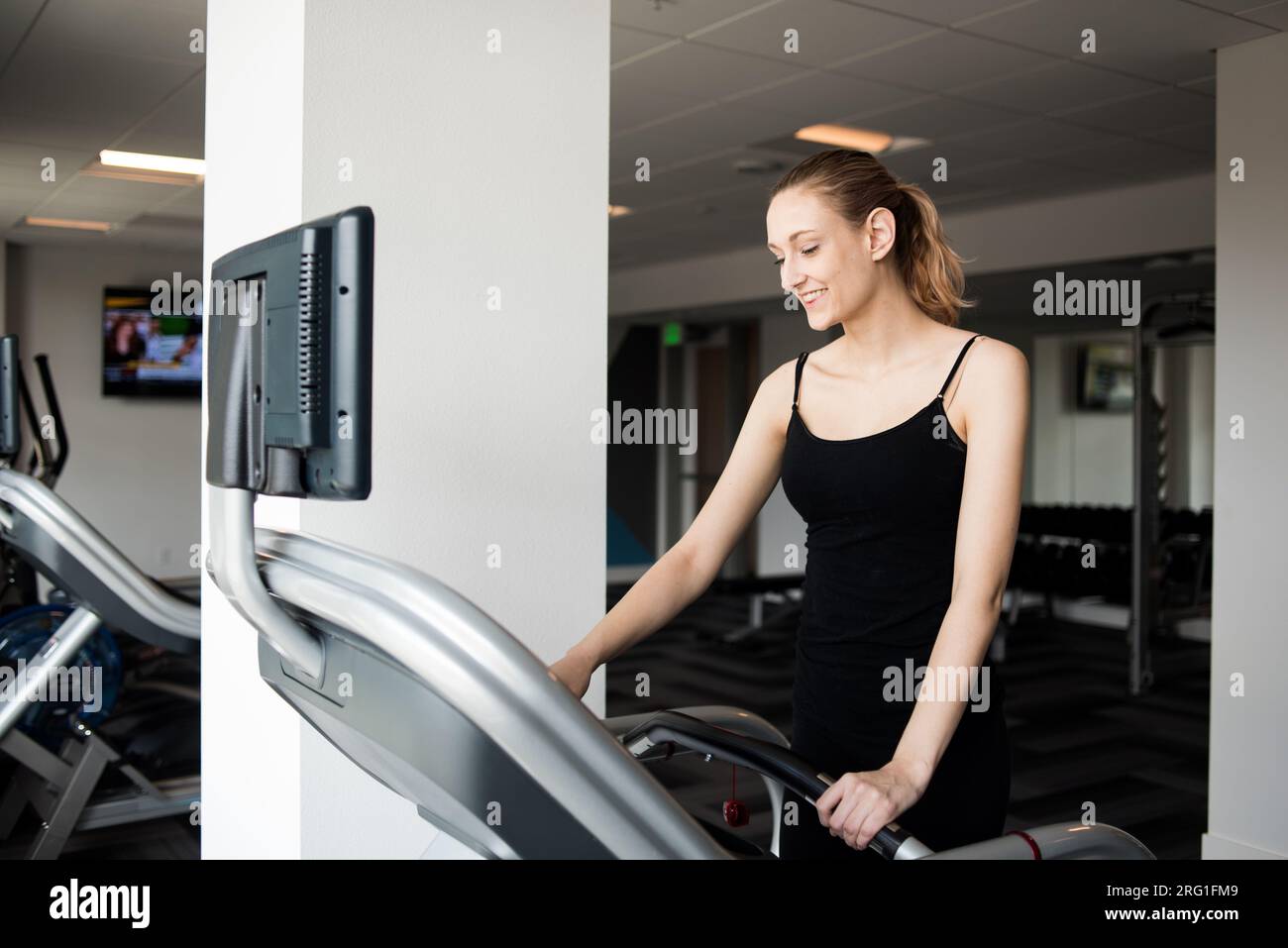 Woman turning on treadmill before workout Stock Photo - Alamy