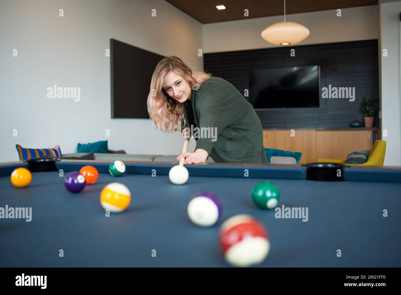 Focused woman playing pool in apartment Stock Photo - Alamy