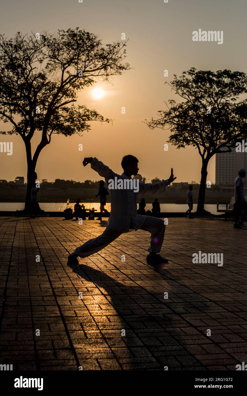 Silhouette of a young adult practising Tai Chi at sunset time, Phnom ...