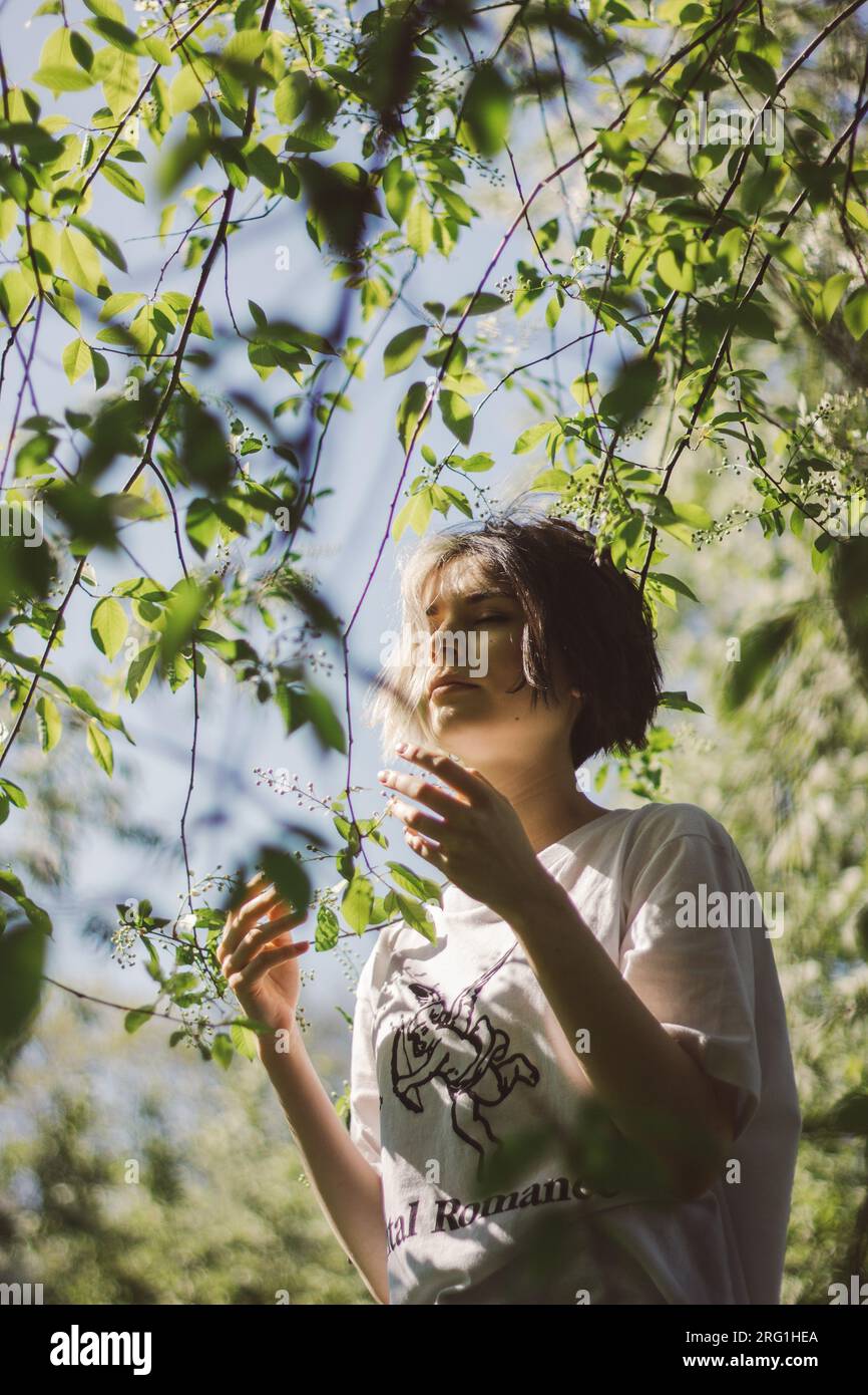 Portrait of a young girl with closed eyes under the sun under a tree ...