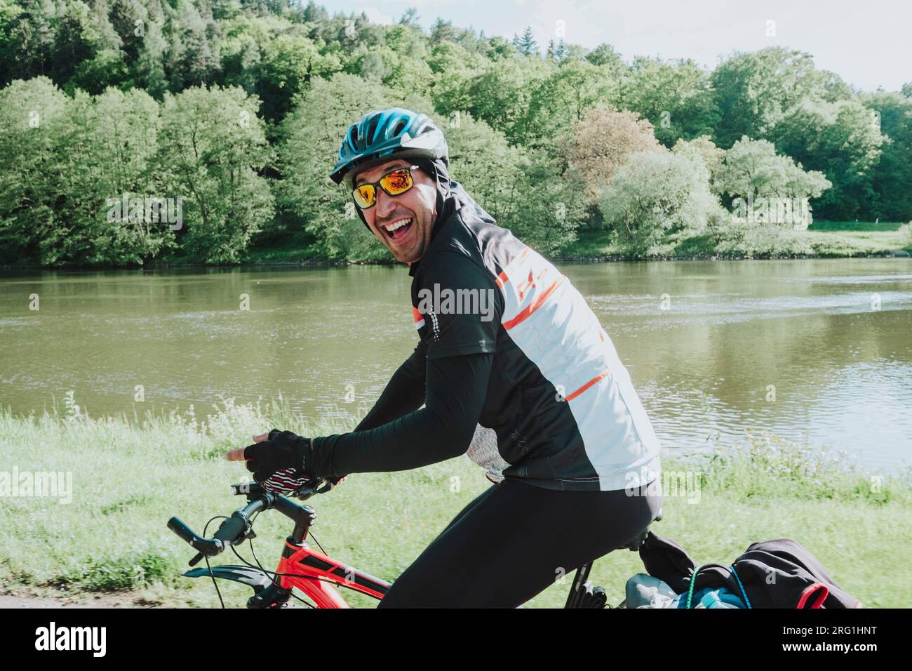 Smiling cyclist riding his bike near to the river Stock Photo - Alamy