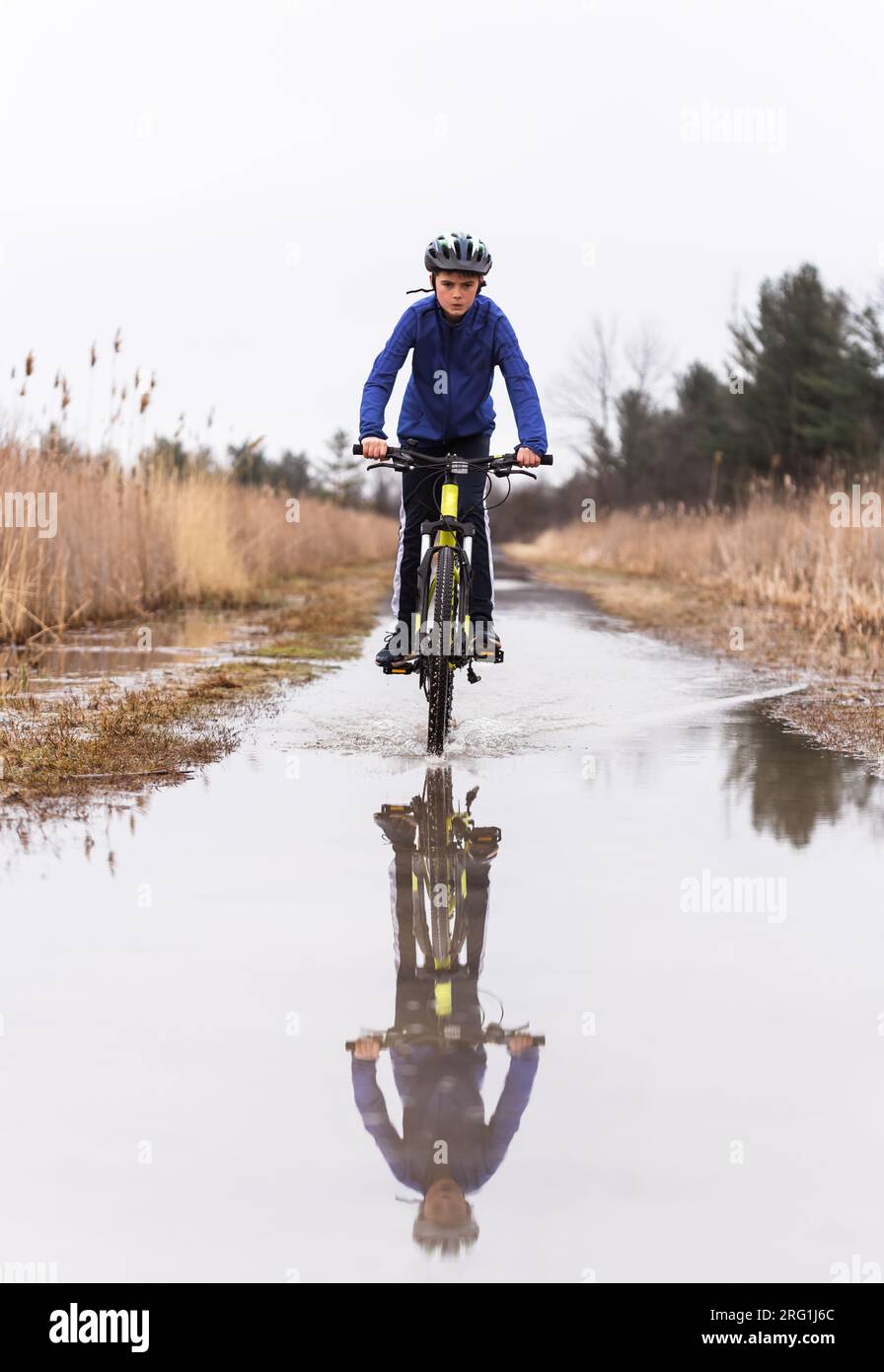 Boy riding his mountain bike through a puddle on a flooded trail Stock ...