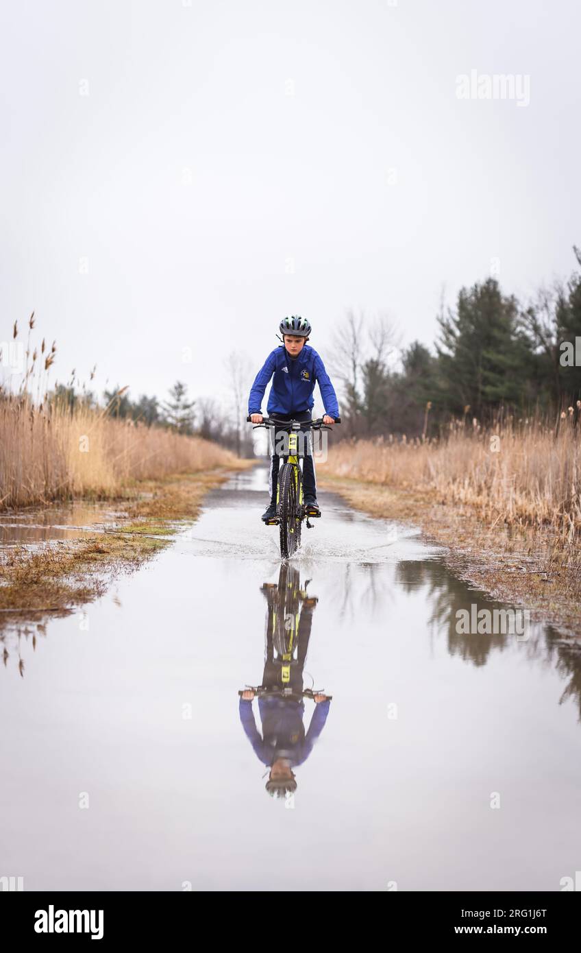 Boy riding his mountain bike through a puddle on a flooded trail Stock ...