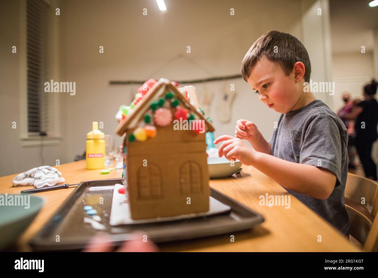 side view of young boy decorating a gingerbread house Stock Photo - Alamy