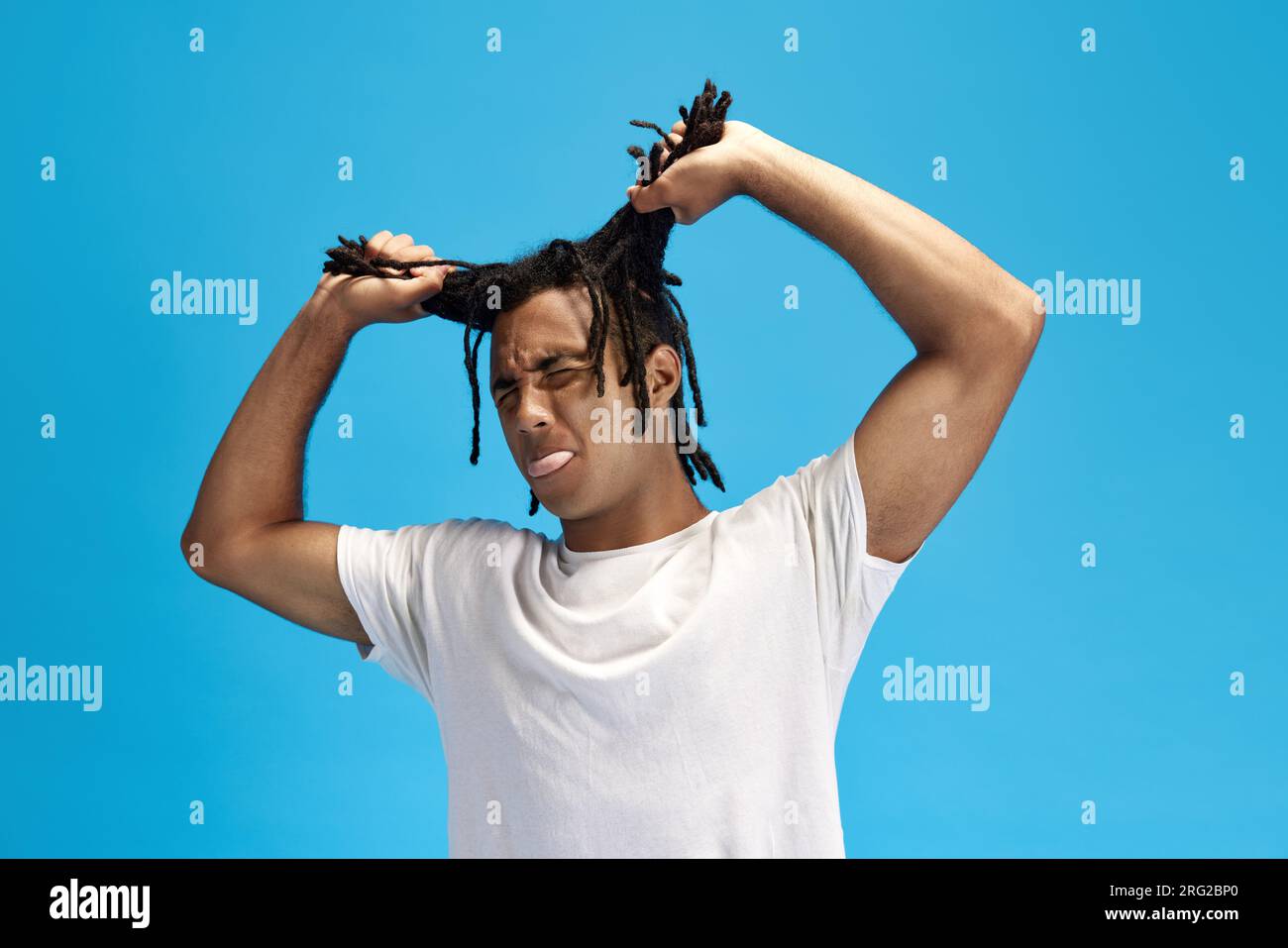 Meme look. Young guy pulling hair, dreads and sticking out tongue ...