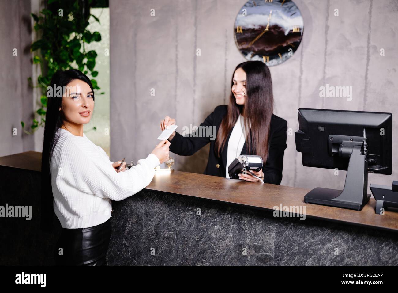 Friendly young concierge standing behind a reception counter giving ...