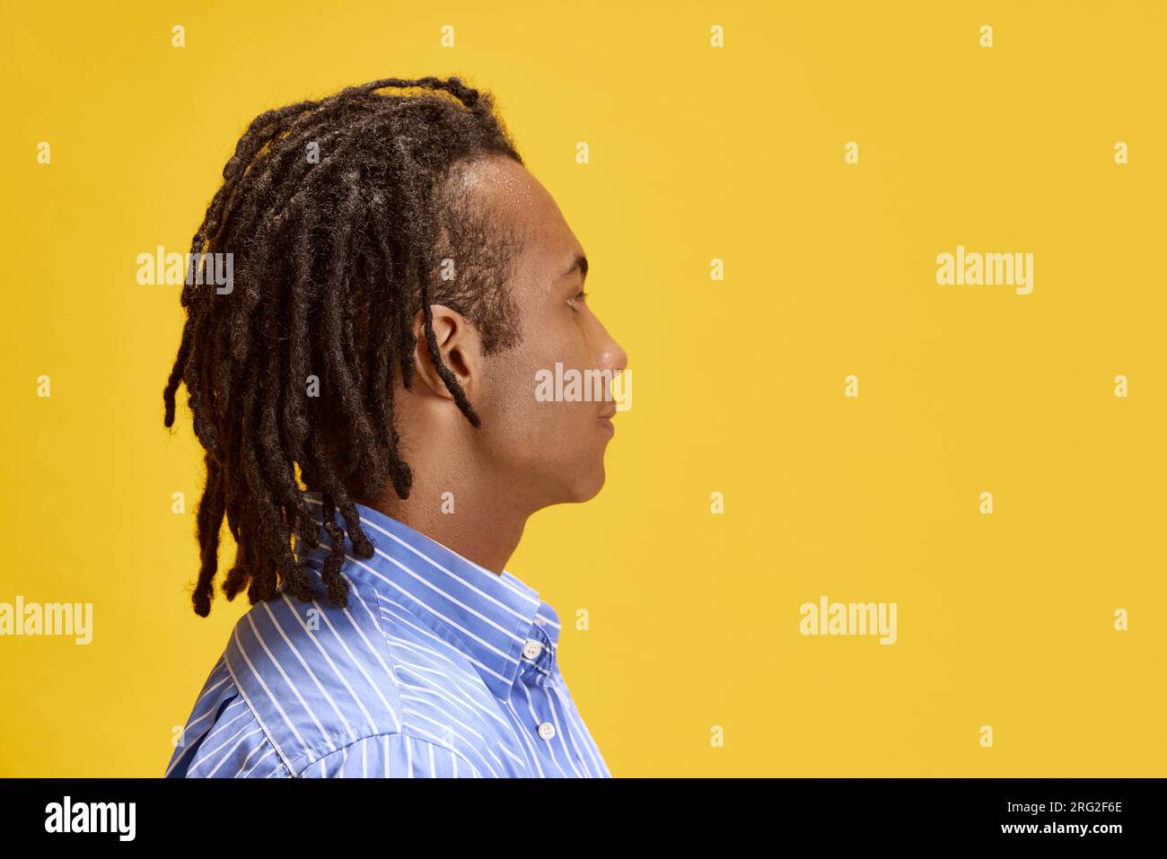 Side view portrait of young african man with dreads in shirt looking ...