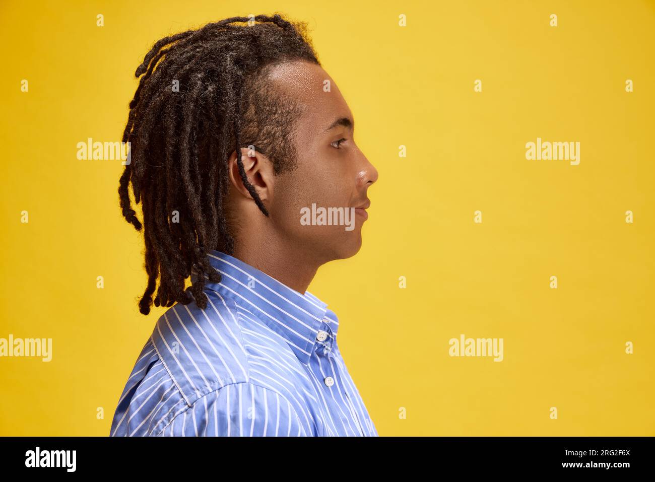 Side view portrait of young african man with dreads in shirt looking ...