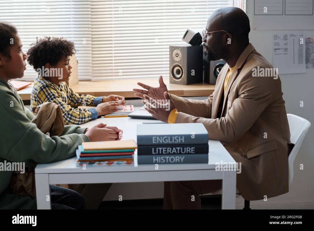 African American teacher having conversation with school children while ...