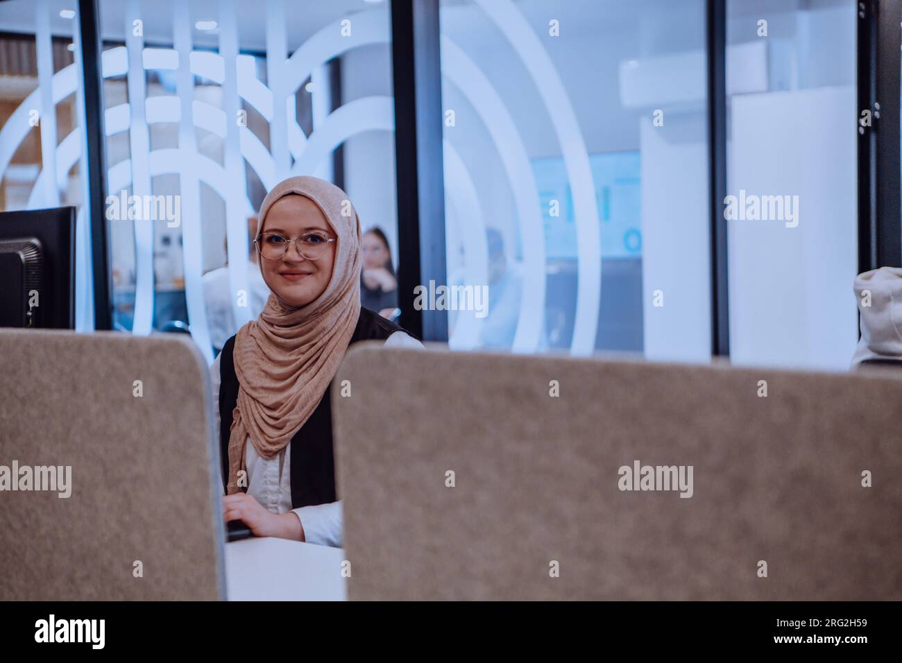 In a modern office, a young Muslim entrepreneur wearing a hijab sits ...