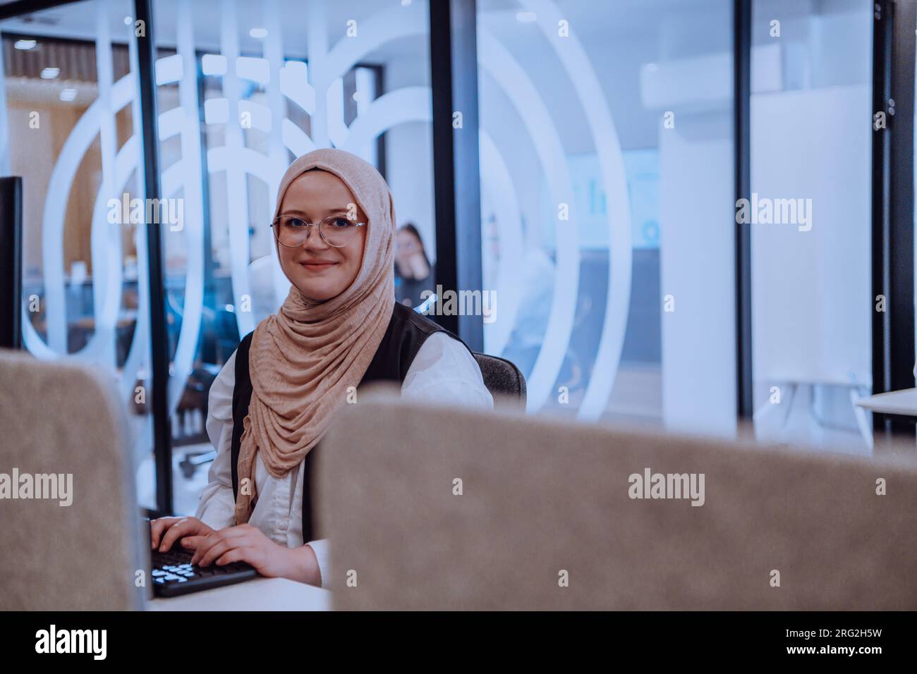 In a modern office, a young Muslim entrepreneur wearing a hijab sits ...