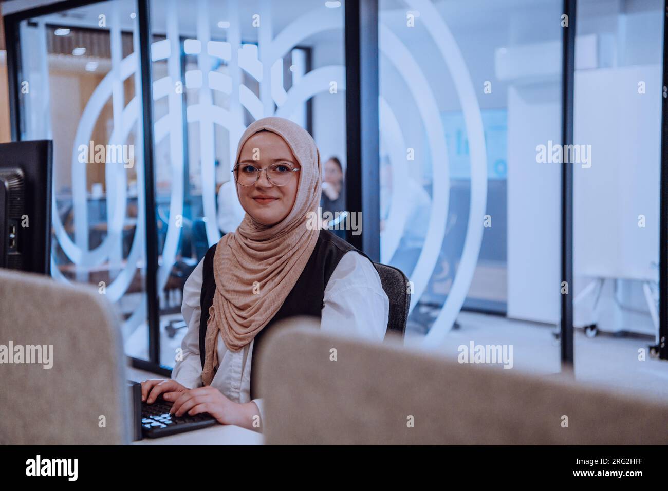 In a modern office, a young Muslim entrepreneur wearing a hijab sits ...