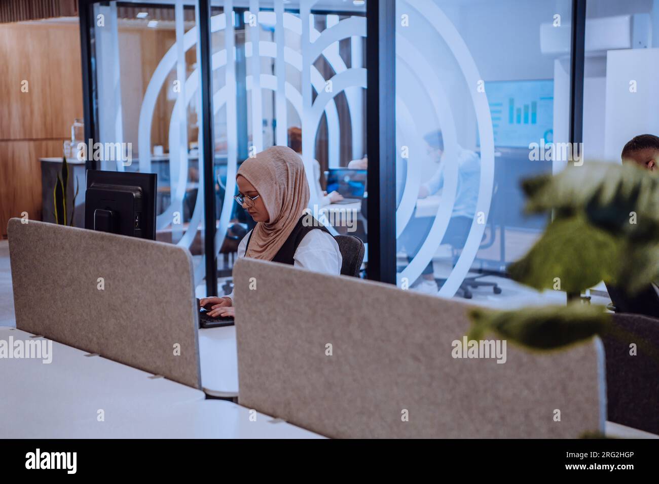In a modern office, a young Muslim entrepreneur wearing a hijab sits ...