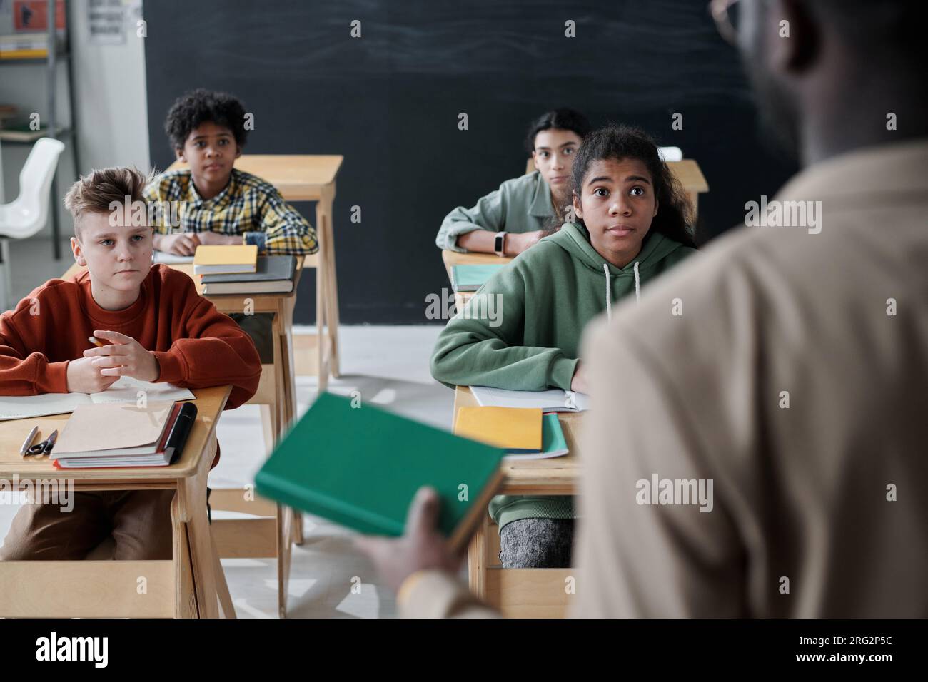 Group of primary school children listening to teacher at lesson at ...