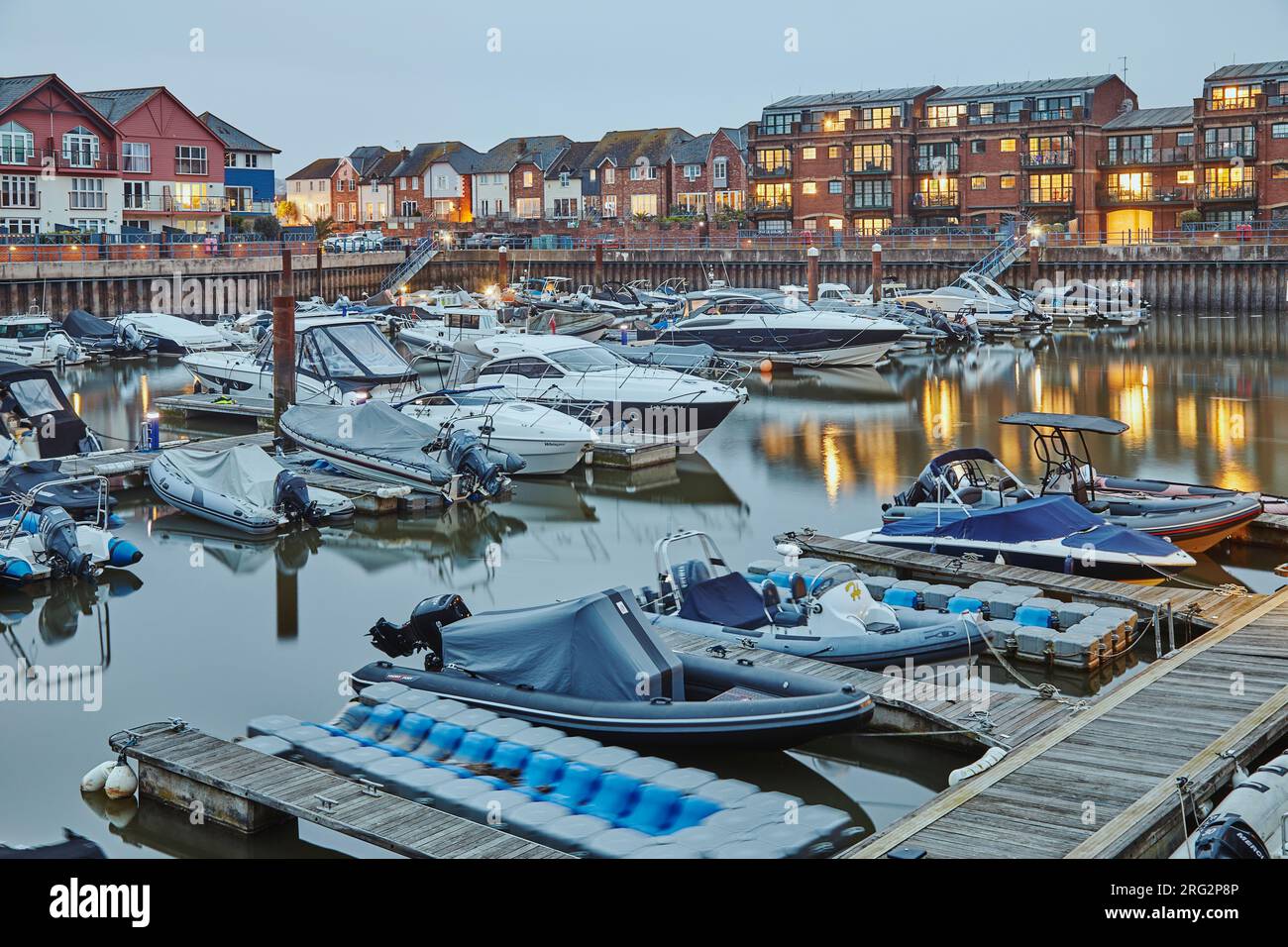 A dusk view of a harbour or marina, surrounded by modern apartment ...