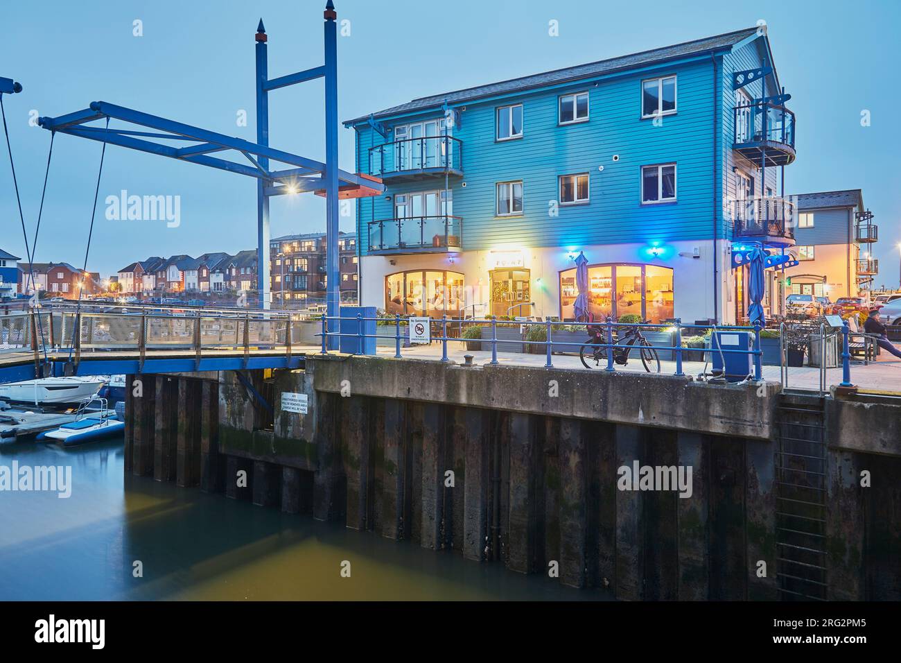 A harbourside cafe and apartment building beside a lifting bridge, seen ...
