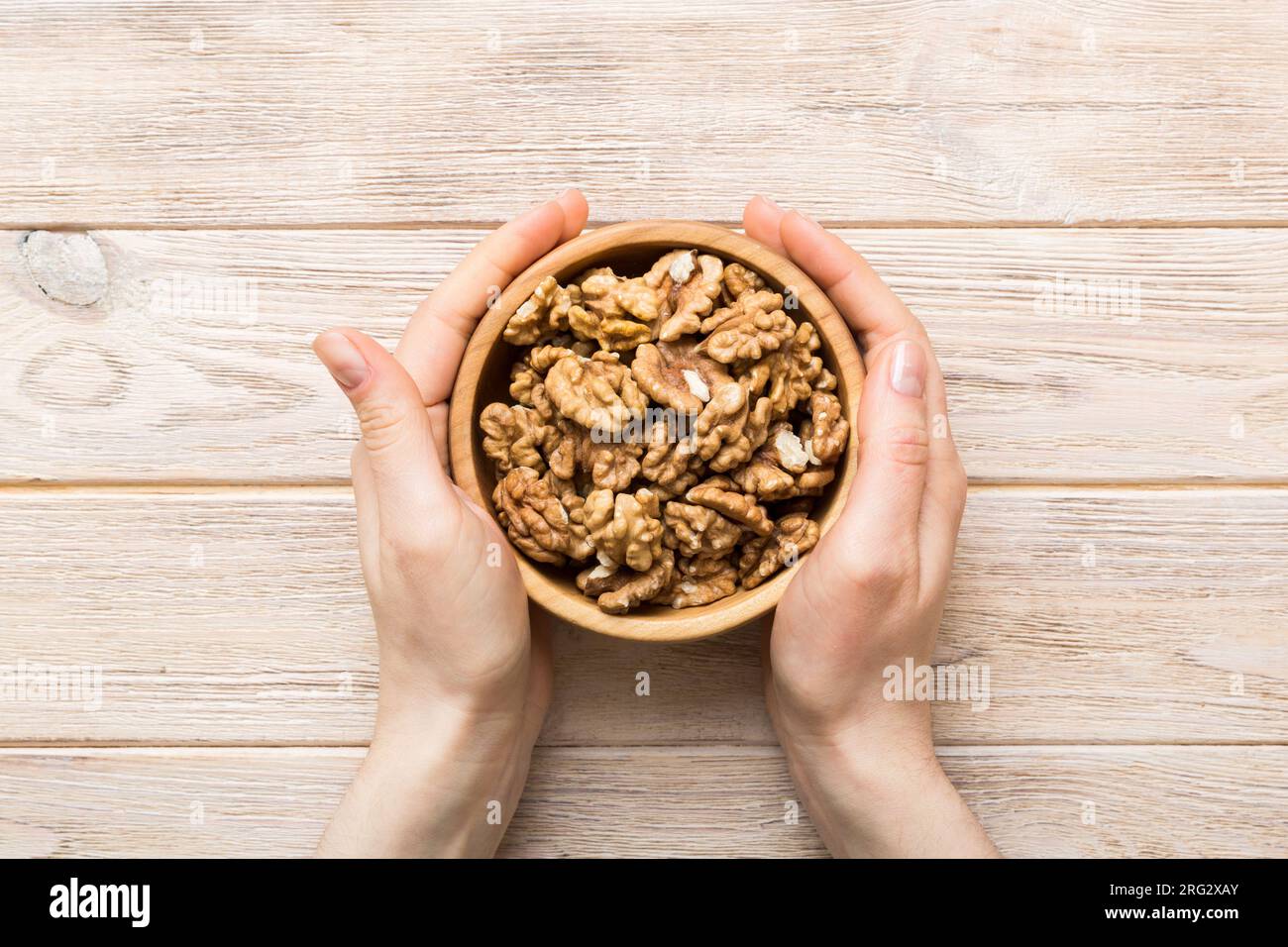 Woman hands holding a wooden bowl with walnut nuts. Healthy food and ...