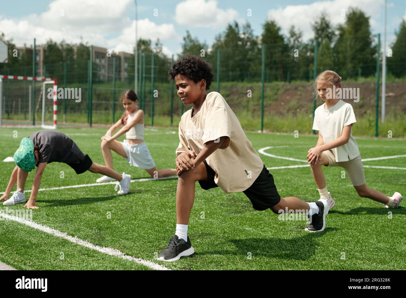 Group of schoolchildren doing physical exercise on green grass of ...