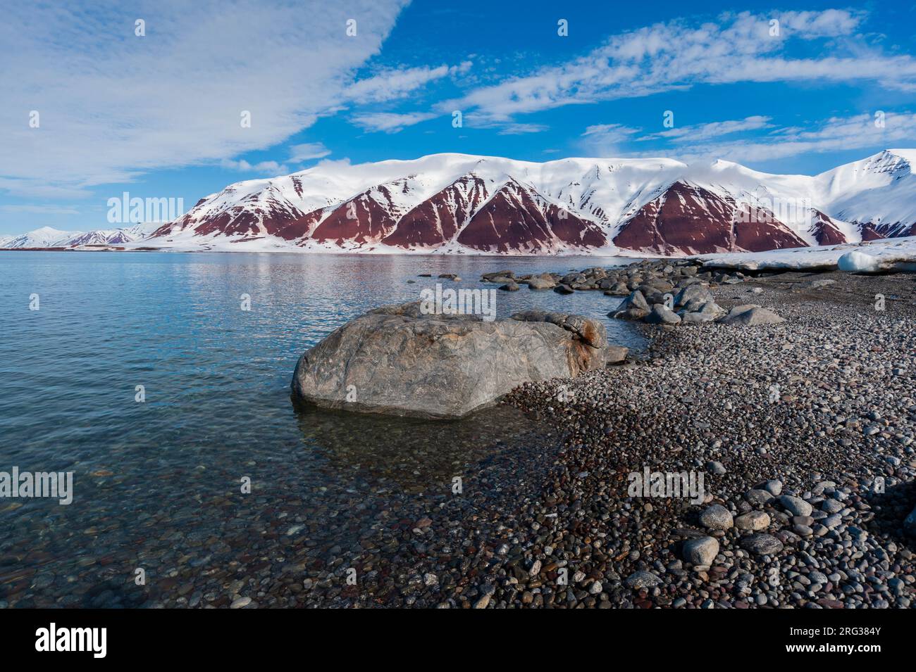 A gravel shoreline and snow covered mountains border Bockfjorden ...