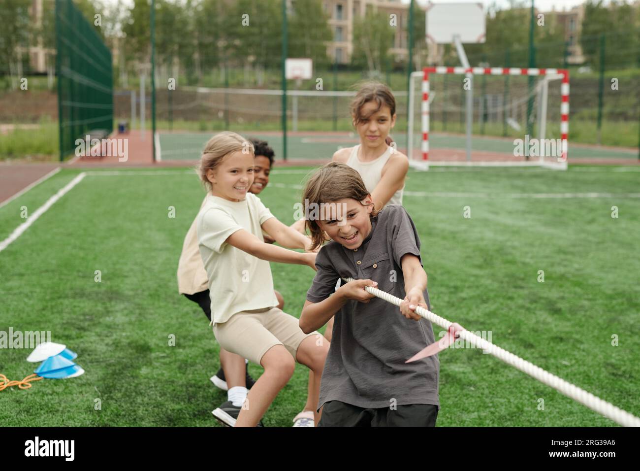 Group of strong and active schoolchildren making effort while pulling ...