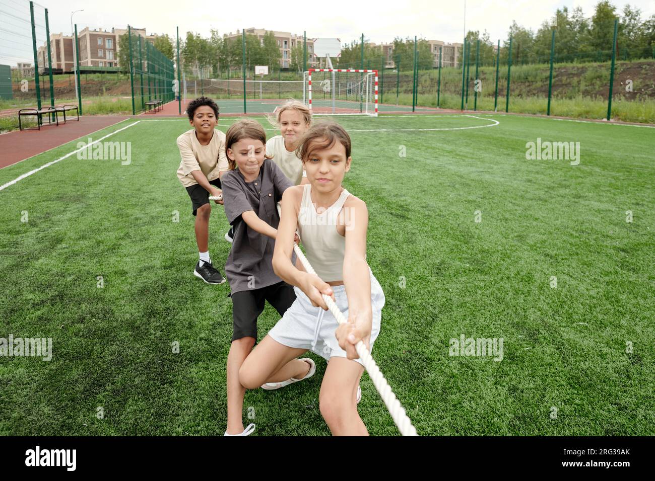 Group of four strong intercultural classmates pulling rope at lesson of ...