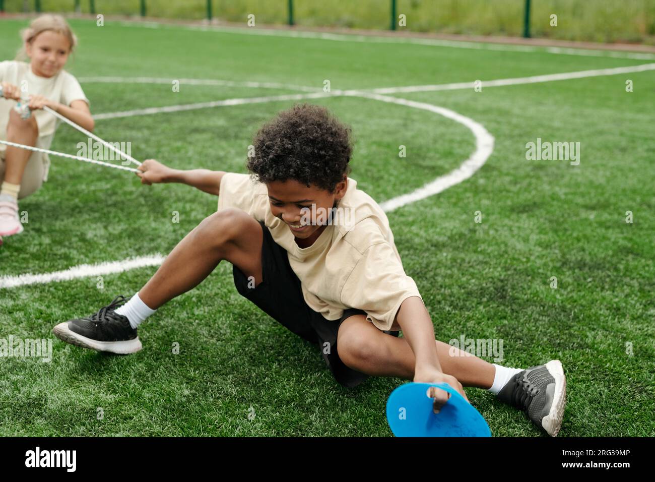 Cheerful African American schoolboy pulling rope and resisting to ...