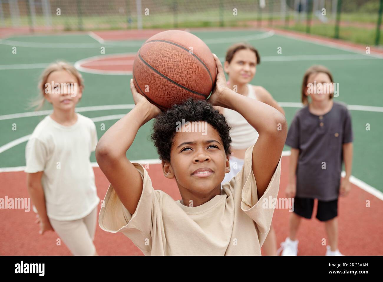 African American schoolboy holding ball over his head while throwing it ...