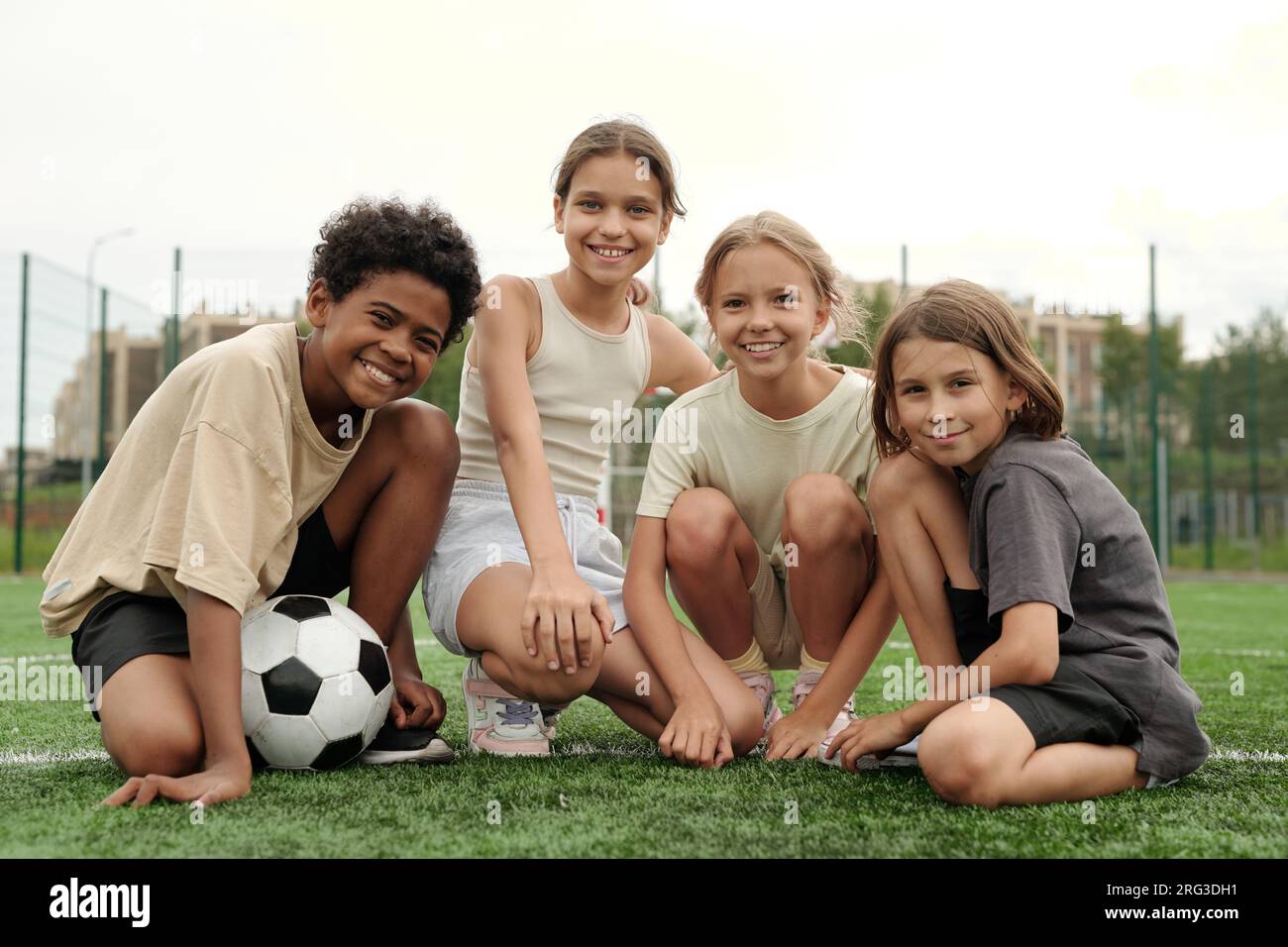 Team of four active friends and football players looking at camera with ...
