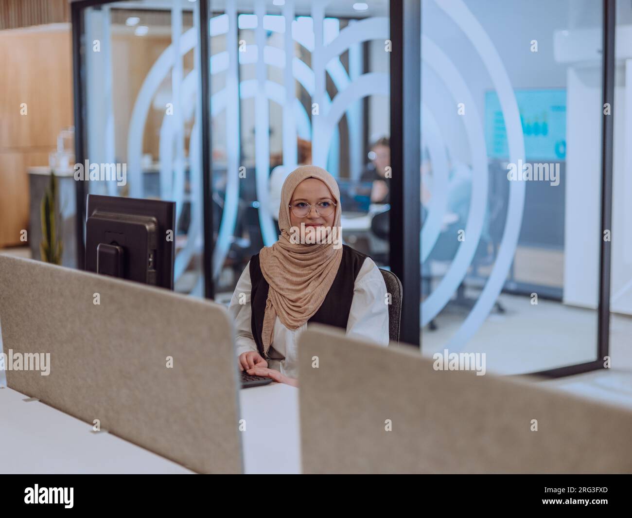 In a modern office, a young Muslim entrepreneur wearing a hijab sits ...